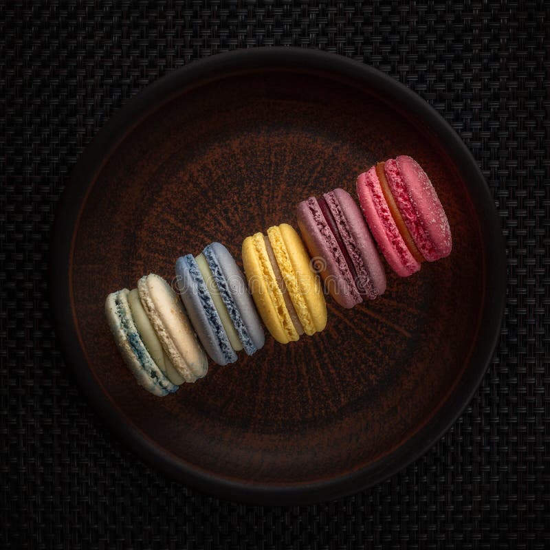Five Colored Macarons on the Brown Plate and Pattern Background Stock ...