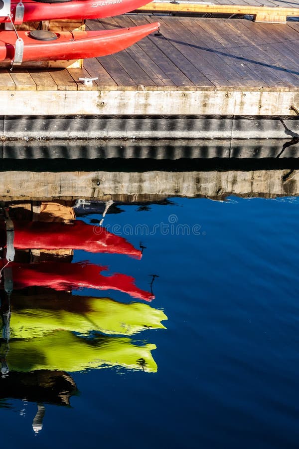 A Row of Red and Yellow Kayaks are Reflected in the Water Stock Photo ...