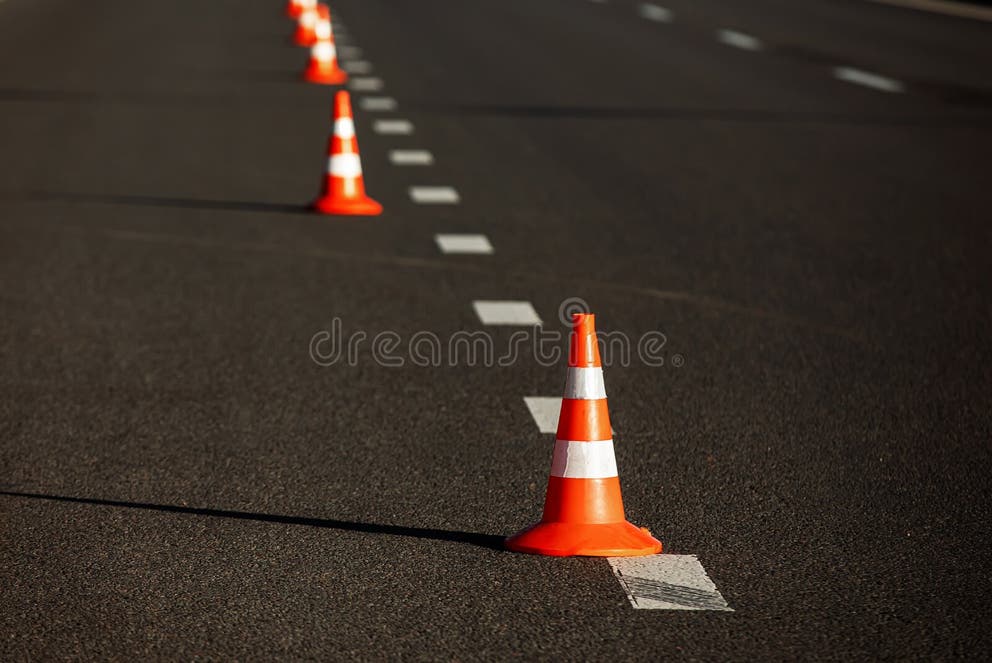 A Row of Traffic Orange Striped Cones on the Road. these Objects are ...