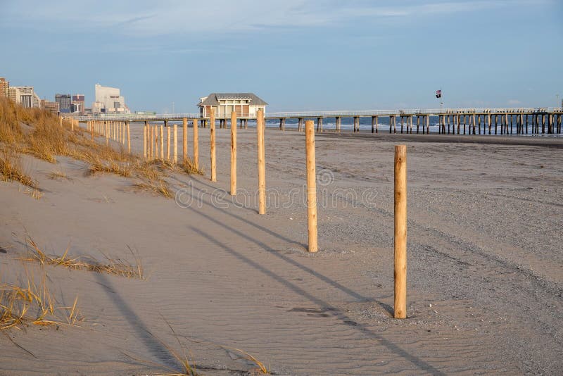 A Row of Wooden Posts on a Beach Near a Pier by a Sand Dune Editorial ...