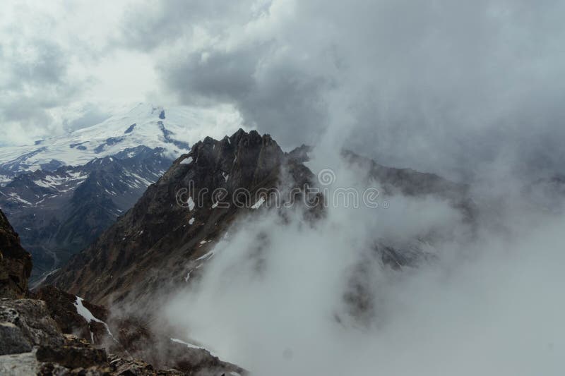 Rugged Mountain Peaks Rise Dramatically into the Sky, Partially Hidden ...