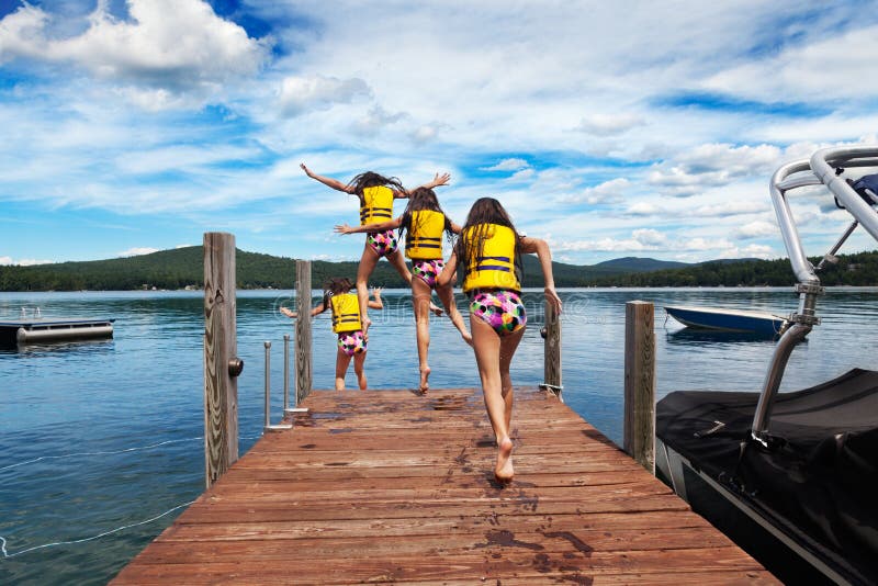 Four Teenage Girls Jumping Off Dock at Lake Stock Photo - Image of lake ...