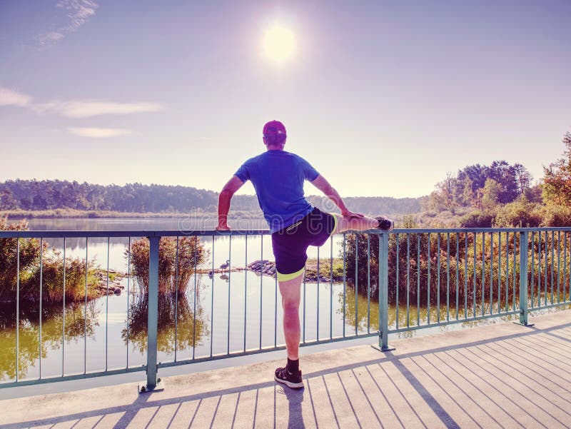 The Runner in Black Leggings Makes Body Stretching on Bridge Path. Sun ...
