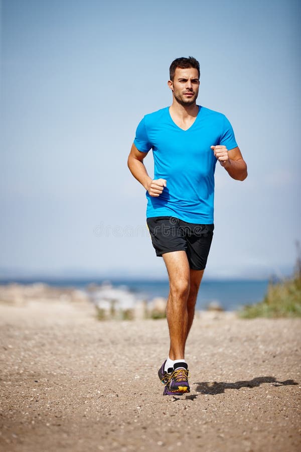 Running Keeps Me Fit. Shot of a Handsome Young Man Running on the Beach ...