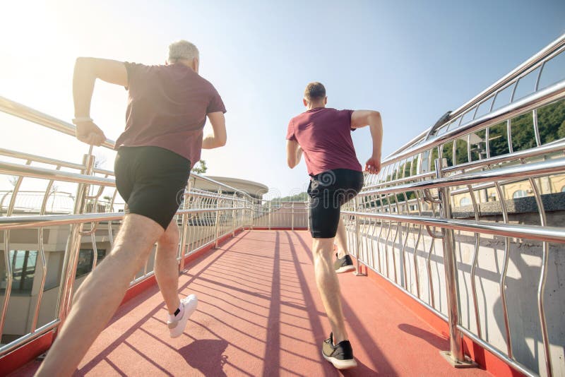Back View of Yound Male and Mature Grey-haired Male Running Across the ...