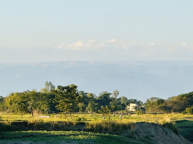 Rural Landscape with Distant Mountain Range and People Working in Field ...
