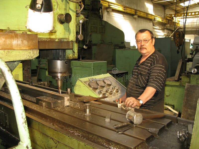 An Elderly Worker Works on a Milling Machine in a Machine Shop during ...