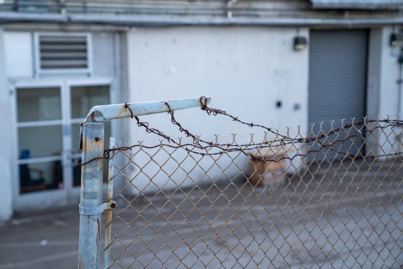 Rusted Barbed Wire on Broken Fence in Front of Warehouse Stock Image ...