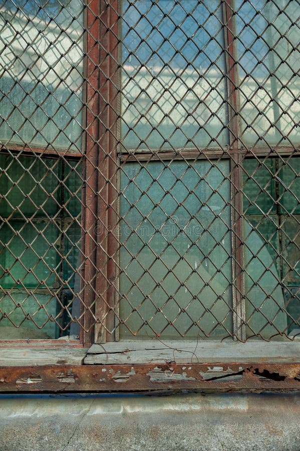 Rusted Metal Grid Guards a Weathered Glass Window in an Old Structure ...