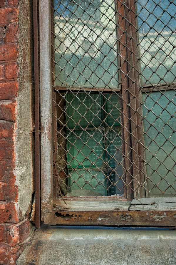 Rusted Metal Grid Guards a Weathered Glass Window in an Old Structure ...