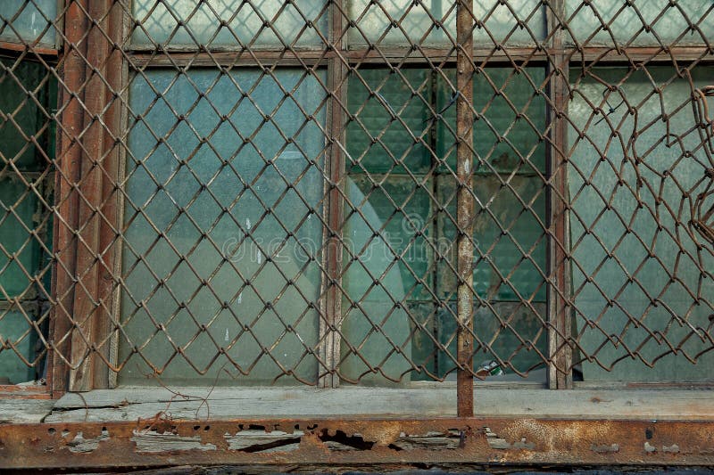 Rusted Metal Grid Guards a Weathered Glass Window in an Old Structure ...