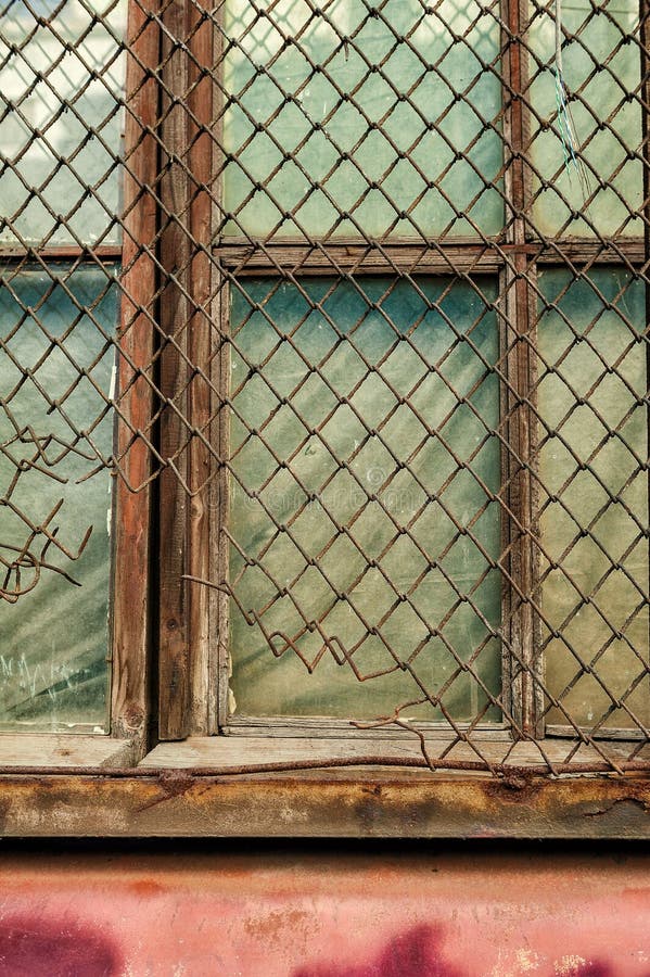 Rusted Metal Grid Guards a Weathered Glass Window in an Old Structure ...