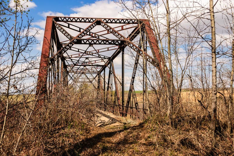 A Rusted Old Bridge with a Lot of Weeds and Trees in the Background ...