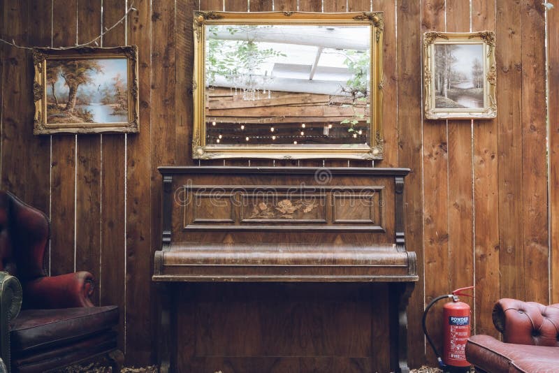 A Rustic Antique Piano with a Mirror Above and a Weathered Wooden Wall ...