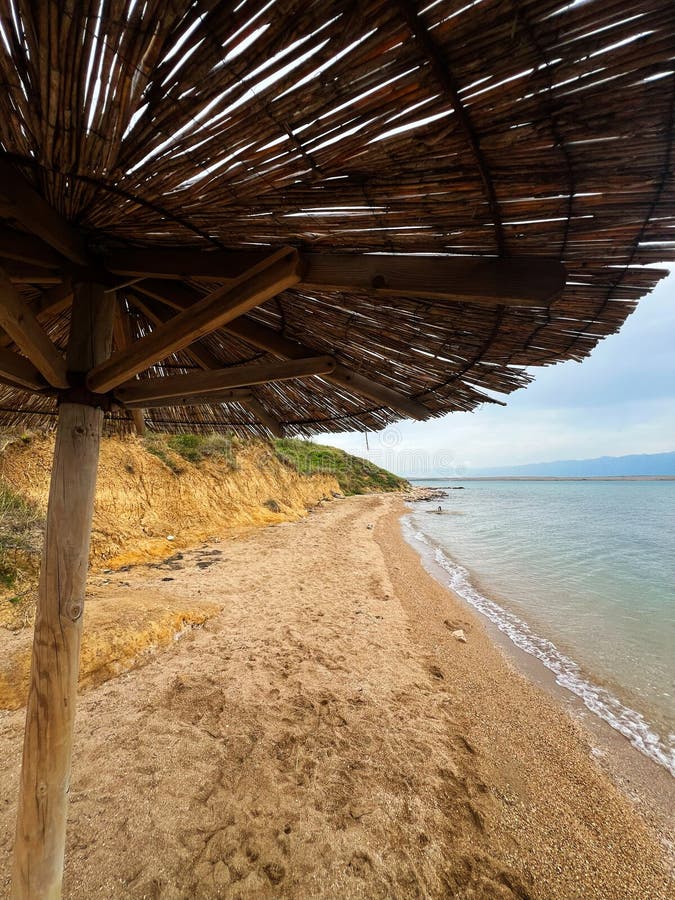 Rustic Beachfront Scene with Bamboo Parasol and Tranquil Waves Stock ...