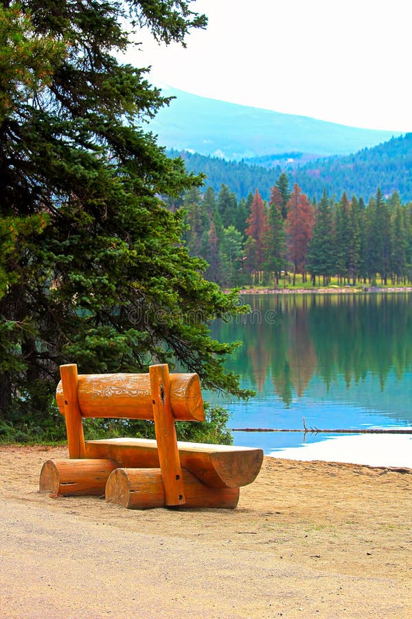 A Rustic Bench Sits on a Calm Lake Shore in the Mountains Stock Image ...