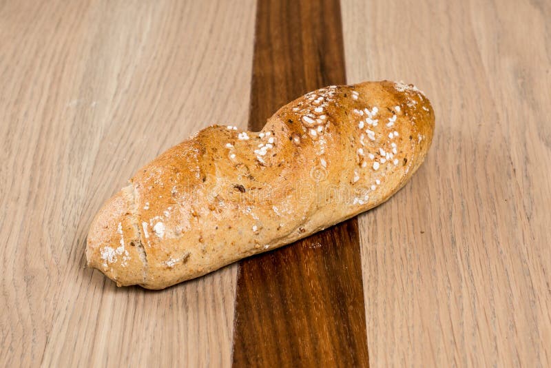 Rustic Bread Roll with Seeds Resting on a Two Tone Wooden Surface ...