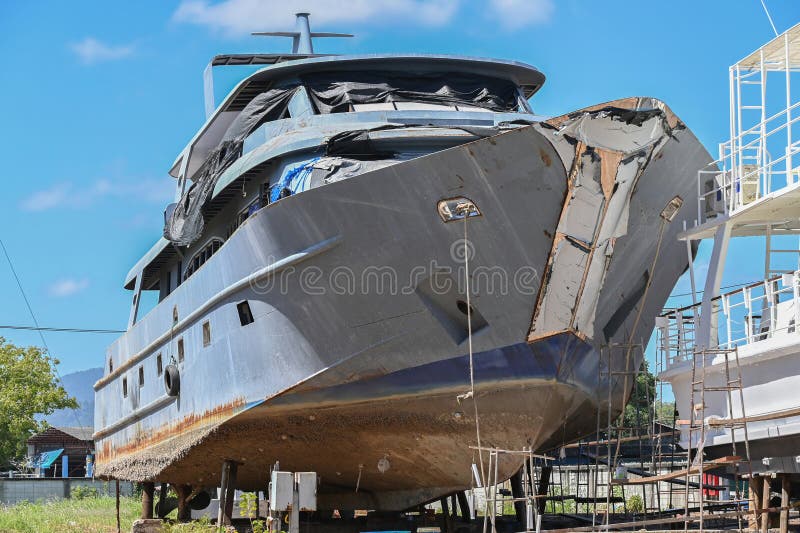A Rustic Broken Yacht Ship on Supports in a Shipyard Repairing Facility ...