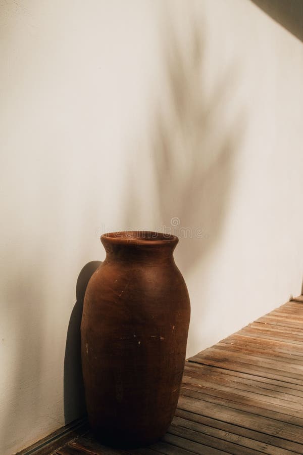 Rustic Clay Vase Casting a Shadow on a Sunlit Deck. Stock Image - Image ...