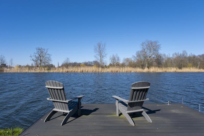 Rustic Hand Crafted Chairs on a Wooden Deck Overlooking a River or Lake ...