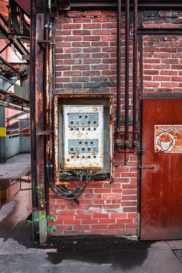 Weathered Industrial Control Panel on Brick Wall with Rusted Pipes and ...