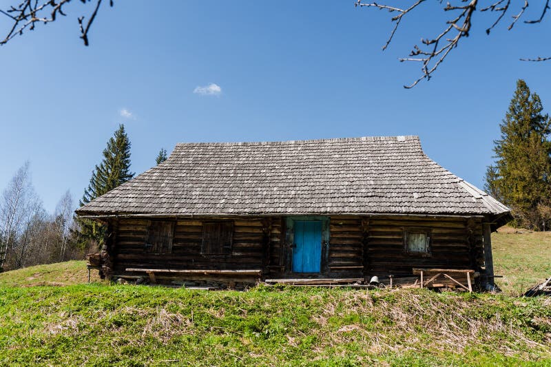 Rustic Log Cabin Under a Clear Blue Sky Surrounded by Greenery and ...