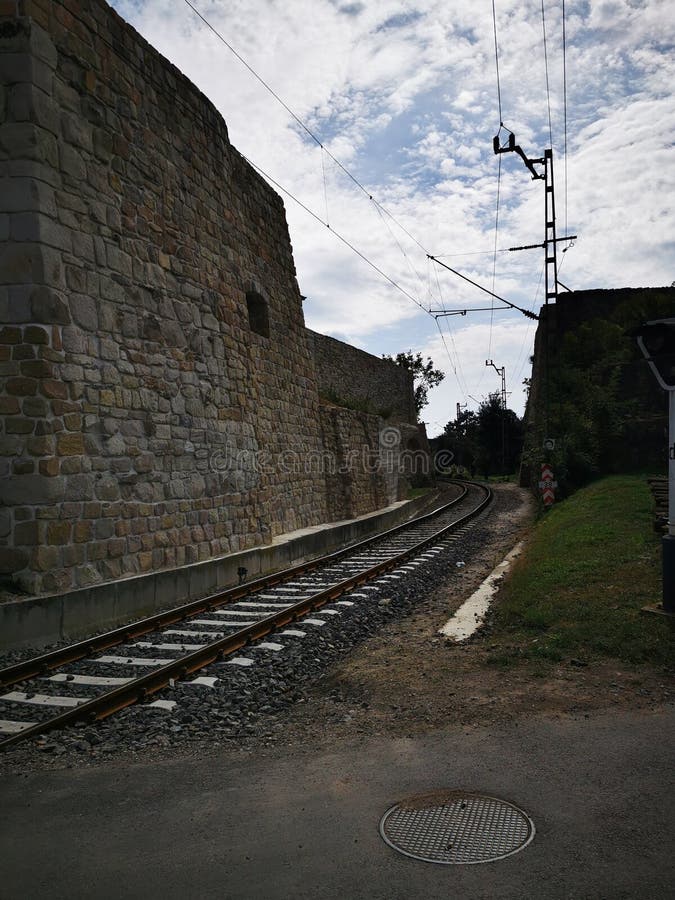 A Quiet Railway Tracks beside Stone Walls Under a Partly Cloudy Sky ...