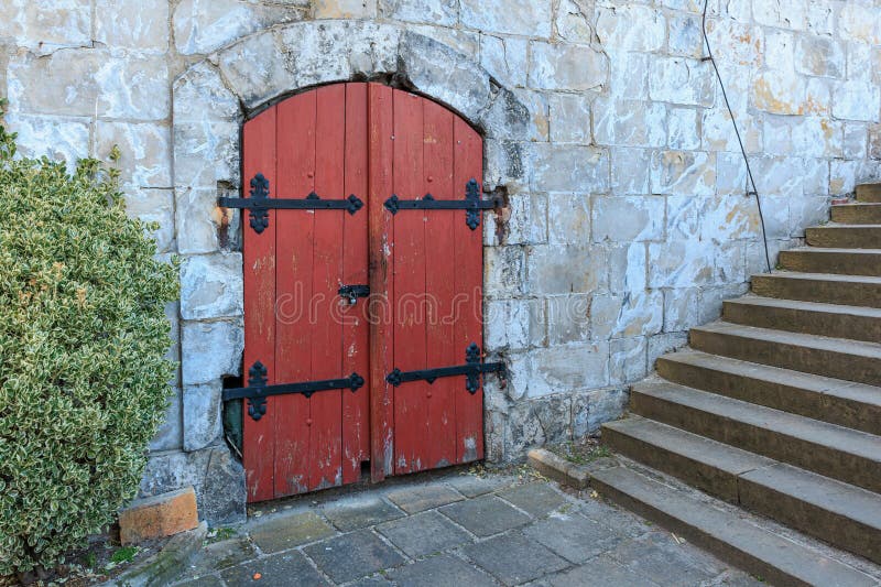 Rustic Red Wooden Door Set in Stone Wall with Staircase and Greenery ...