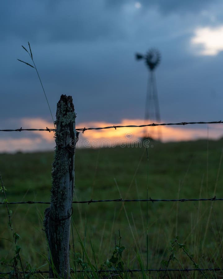 Rustic Scene of a Barbed Wire Fence Post with a Windmill in the ...