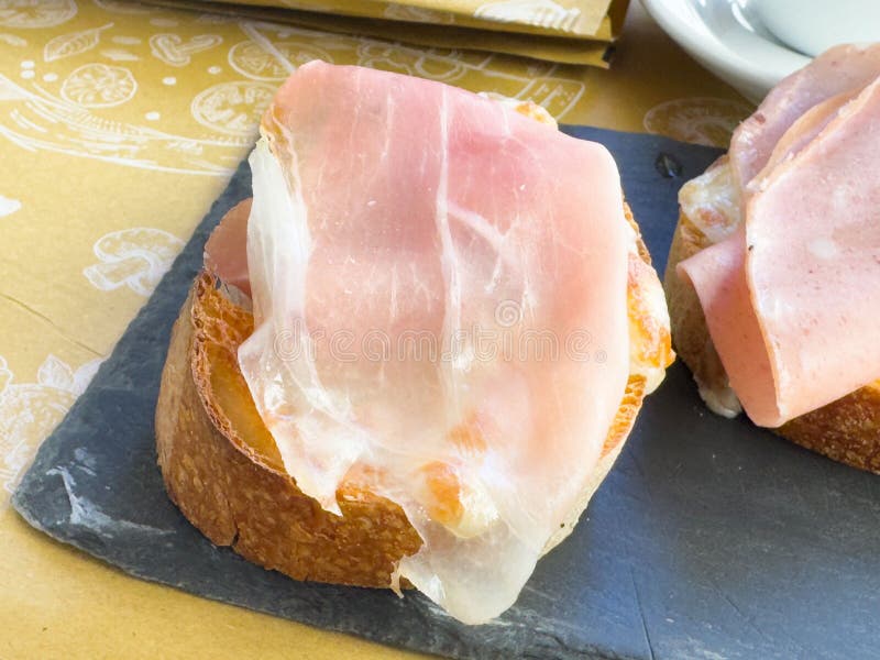 Rustic Sourdough Bread with Prosciutto on Slate Plate in a Cafe Setting ...