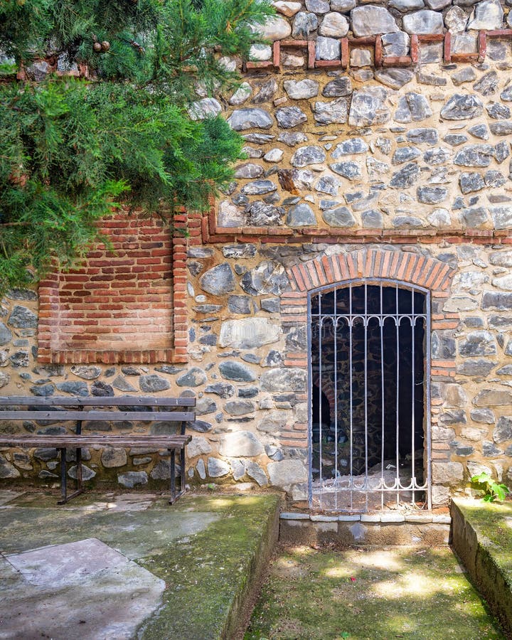 Stone Wall with an Iron Gate and a Bench in a Quiet Garden Area during ...