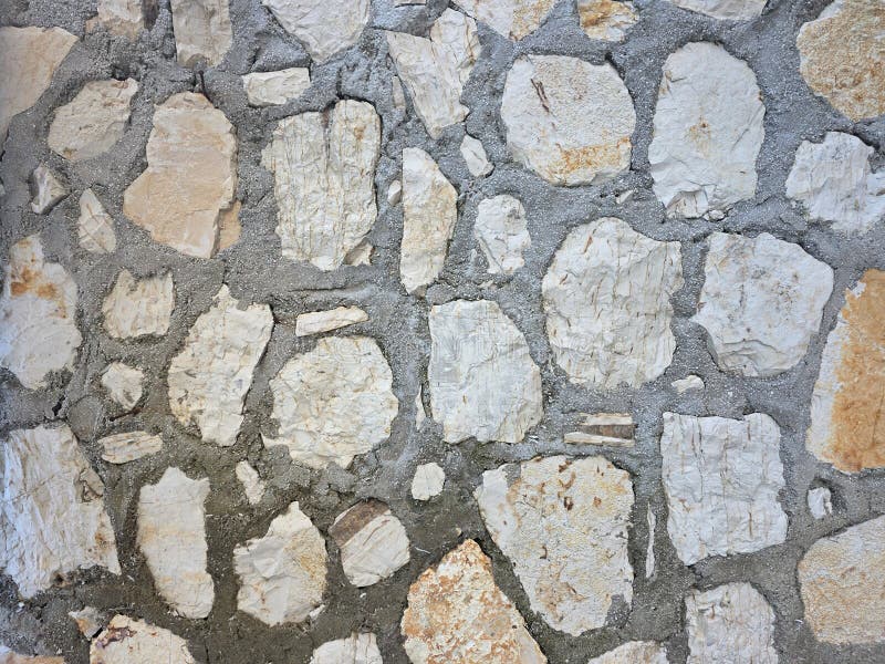 A Rustic Stone Wall Made of Irregular, Light-colored Stones Set in Dark ...