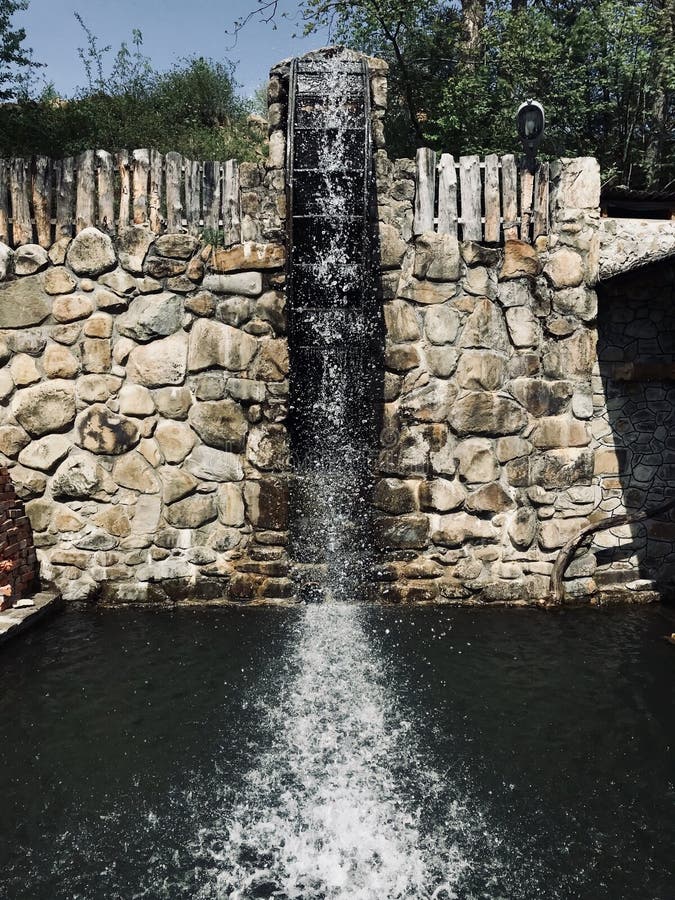 Rustic Stone Waterfall Cascading into Tranquil Pond Setting Stock Photo ...