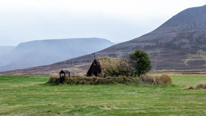 Rustic Turf House Surrounded by Grassy Fields and Mountains Under a ...