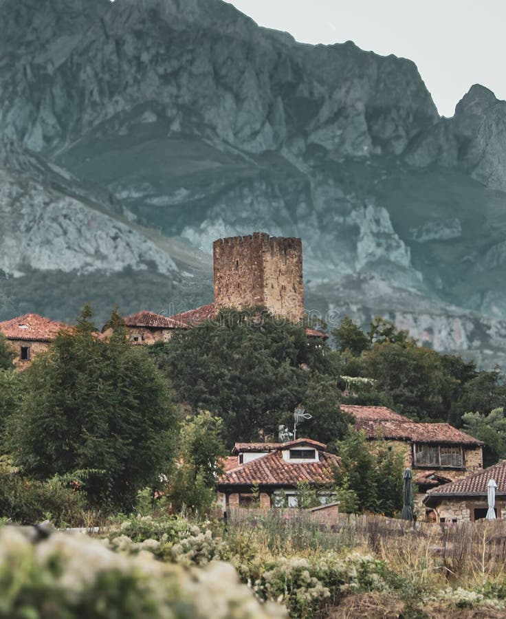 Rustic Village with Ancient Stone Tower and Mountain Backdrop. Stock ...
