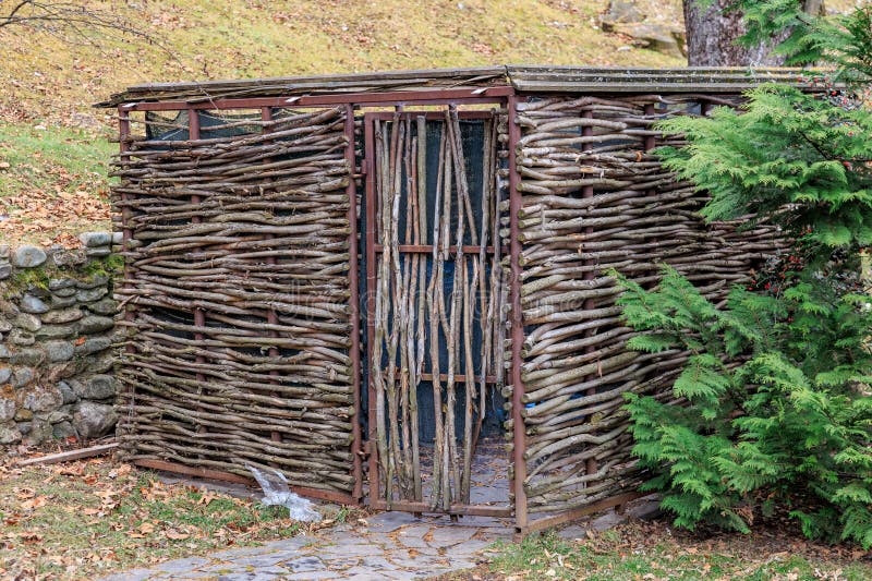 Rustic Wood Branch Hut in Forested Area with Stone Pathway and Greenery ...