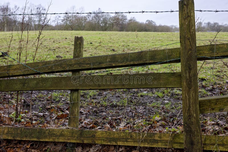 Rustic Wooden Fence with Barbed Wire Facing a Grassy Field Stock Image ...