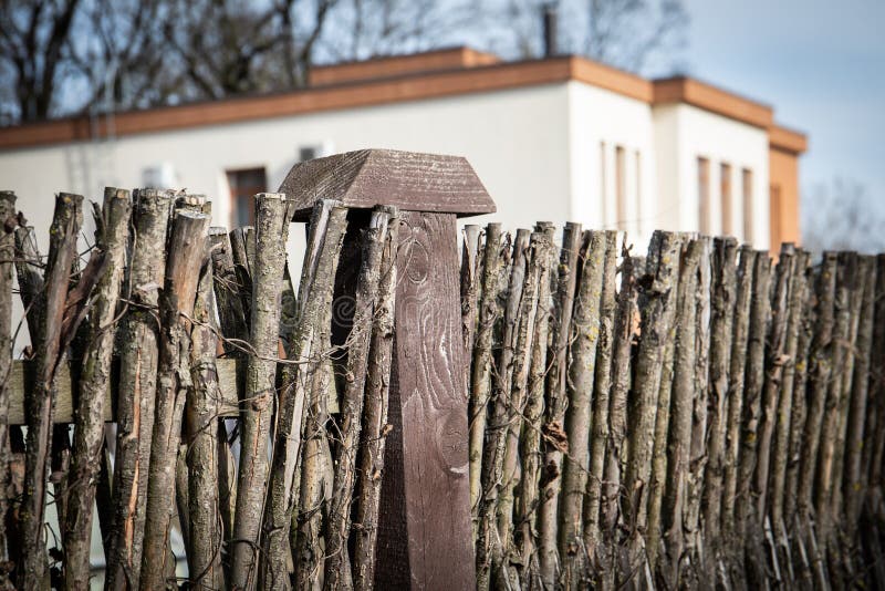 Rustic Wooden Fence with Branches and Modern Building in Background ...
