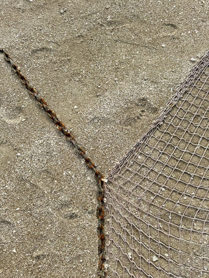 A Rusty Chain and Worn Fishing Net Lay on Coarse Sandy Beach, Their ...
