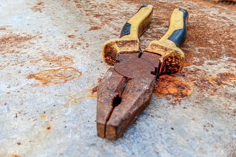Rusty Combination Pliers with Yellow and Black Handles on a Rusty Metal ...