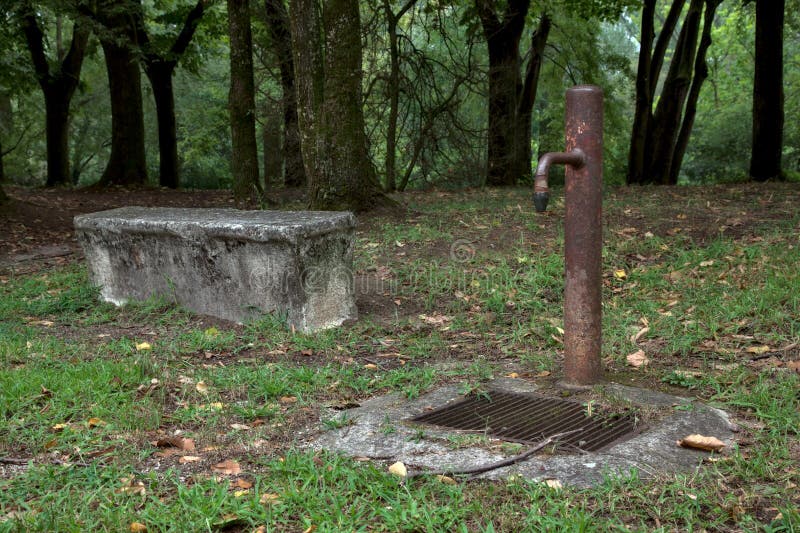 A Rusty Fountain Next To a Stone Bench in a Park on a Cloudy Day Stock ...