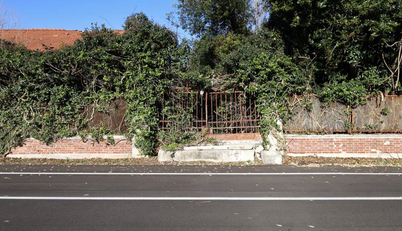 Rusty Gate in the Middle of a Weathered Fence Made of Bricks and Metal ...