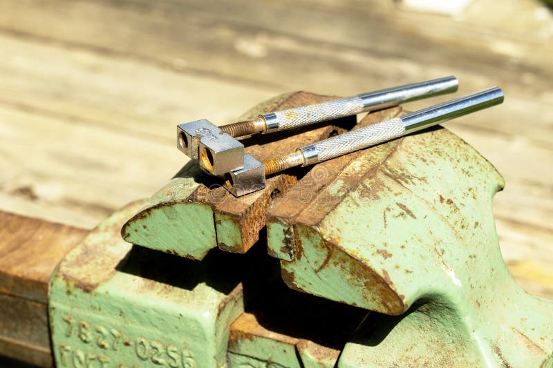 A Rusty Green Vise Holds Two Metal Calipers on a Wooden Surface. the ...