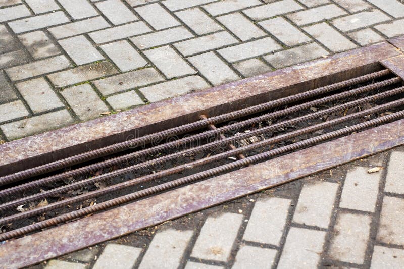 A Rusty Metal Grate is Currently Sitting on a Weathered Brick Sidewalk ...