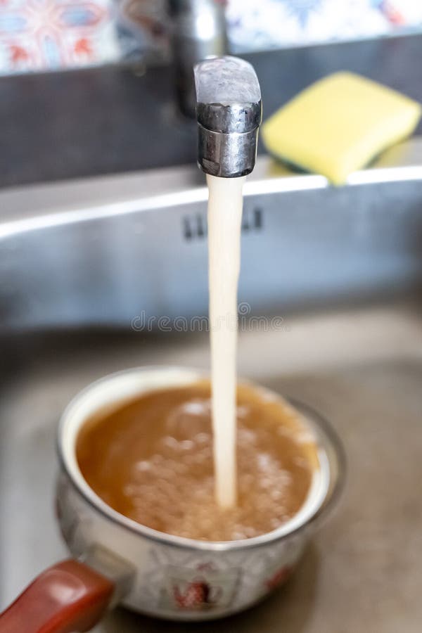 Rusty Orange Water Flows from the Kitchen Faucet into the Pot Stock ...