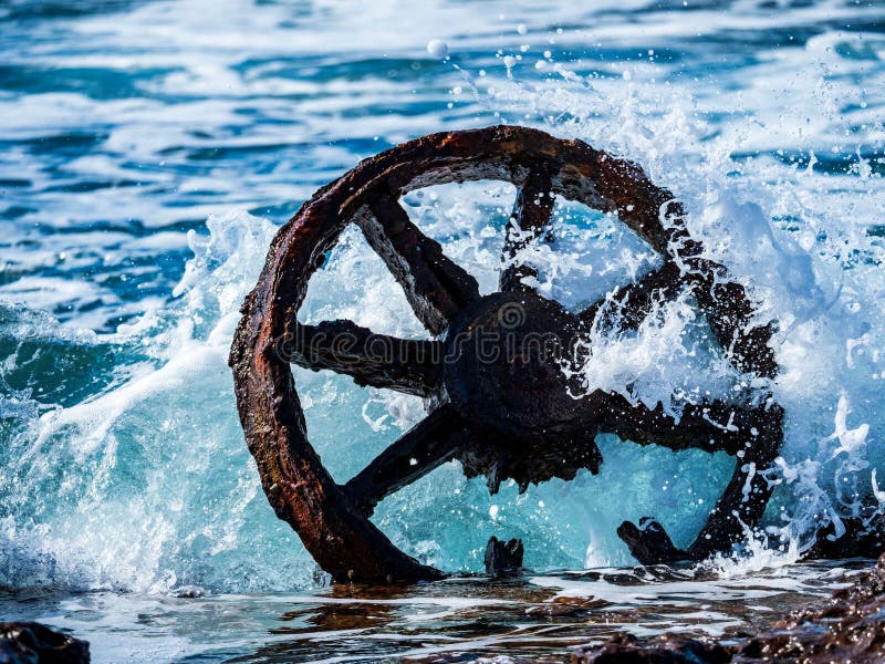 Rusty wheel in ocean waves stock photo. Image of sculpture - 337662566