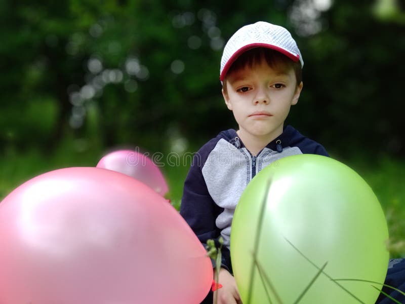 Sad Boy with Balloons Sits on the Grass Stock Photo - Image of sadness ...
