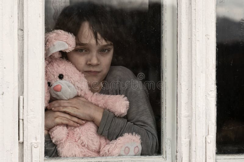 A Sad Boy Looks at the Window. he Holds a Pink Bunny Rabbit with His ...