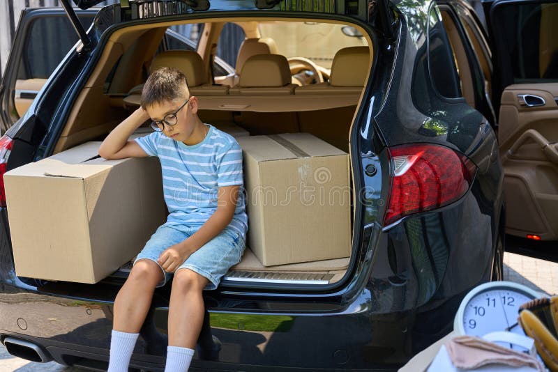 Sad Boy Sits in an Open Trunk between Cardboard Boxes Stock Image ...