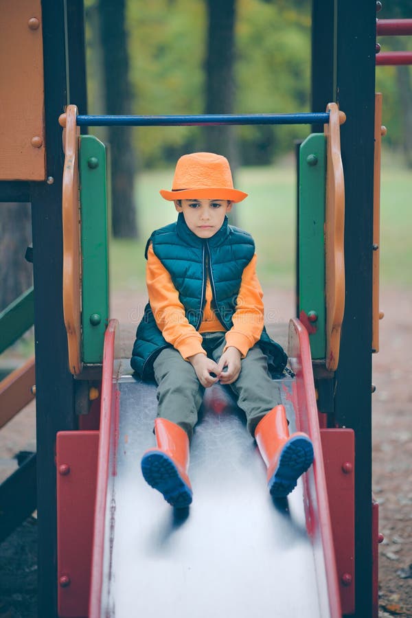 A Sad Child in the Playground on the Slide in the Fall Stock Photo ...